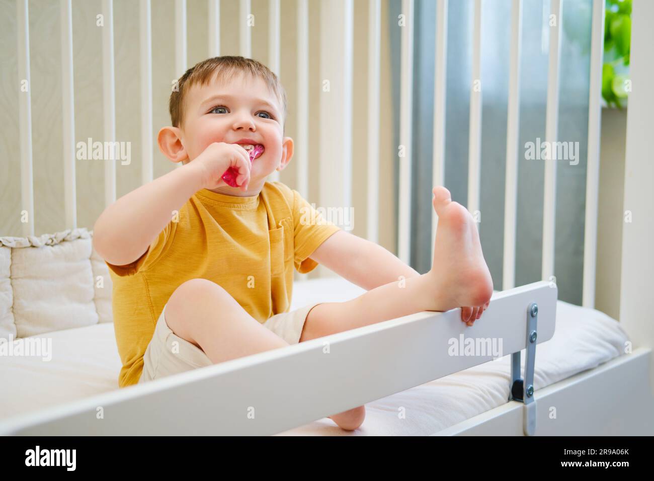 Baby brushing her teeth while sitting in the crib. Kid aged about two ...