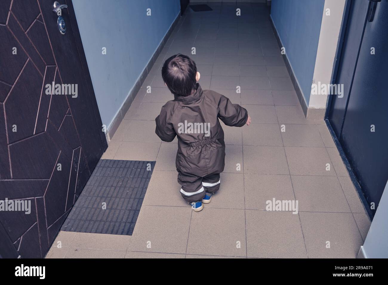 A child walks down the corridor of an apartment building. Baby comes ...
