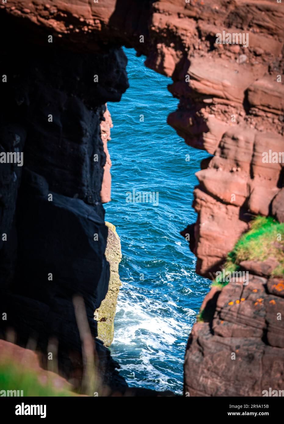 A rocky cliff, featuring a natural archway that frames the beautiful ...