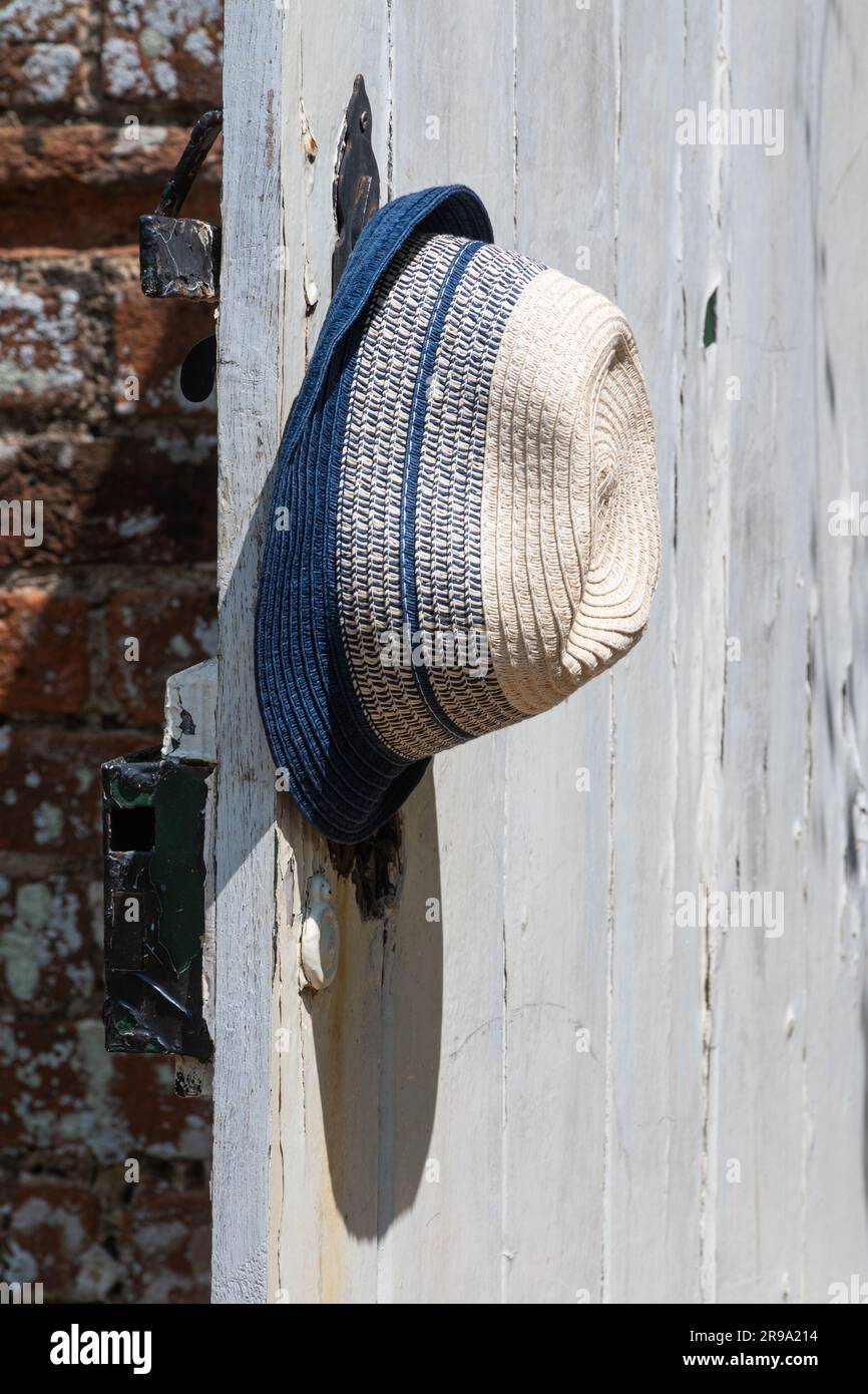 A sun hat hanging on a door to a walled garden in summer, England, UK ...
