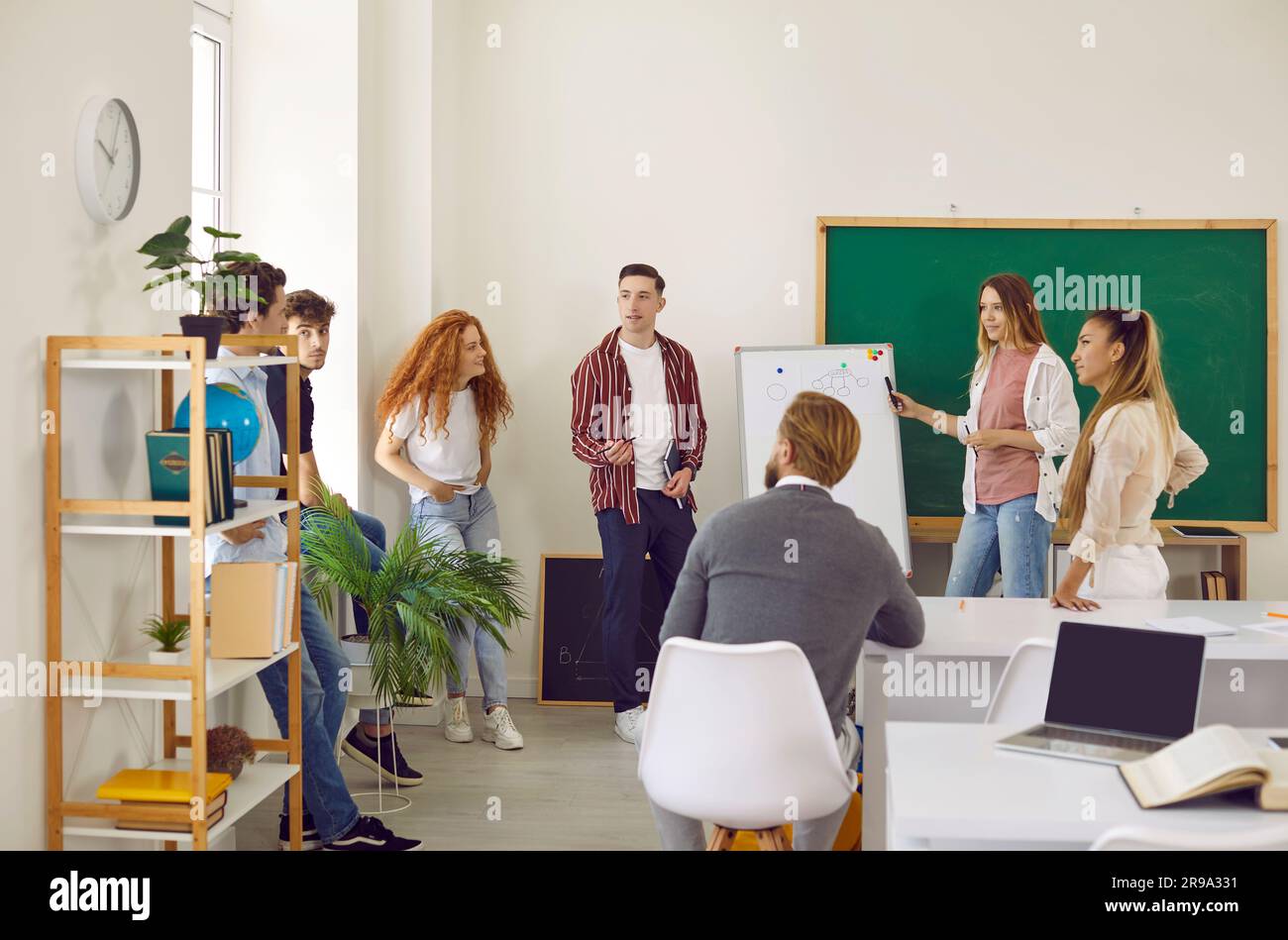 Group of college students and teacher discuss project using whiteboard ...