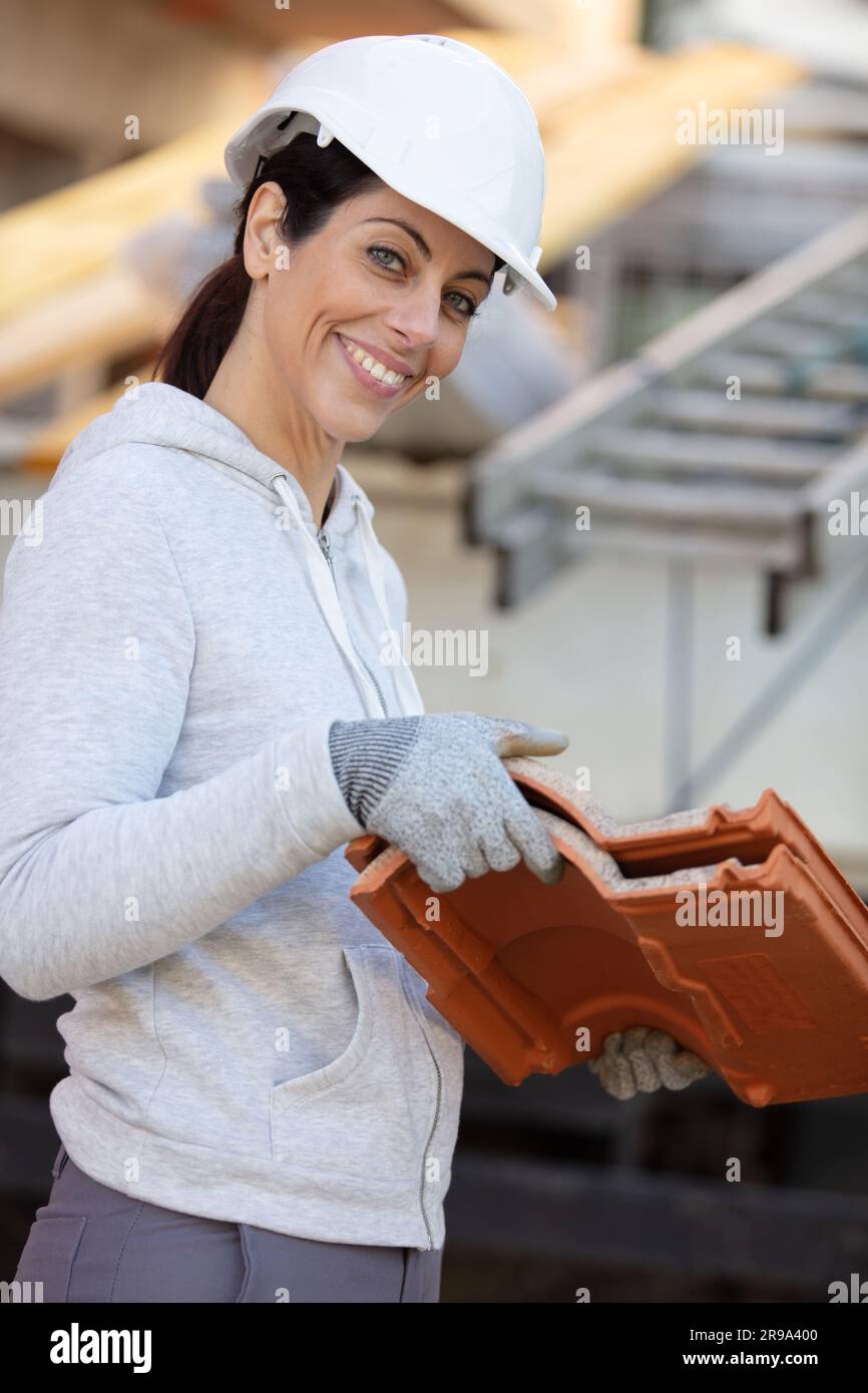 happy female construction worker on site laying slate tiles Stock Photo ...