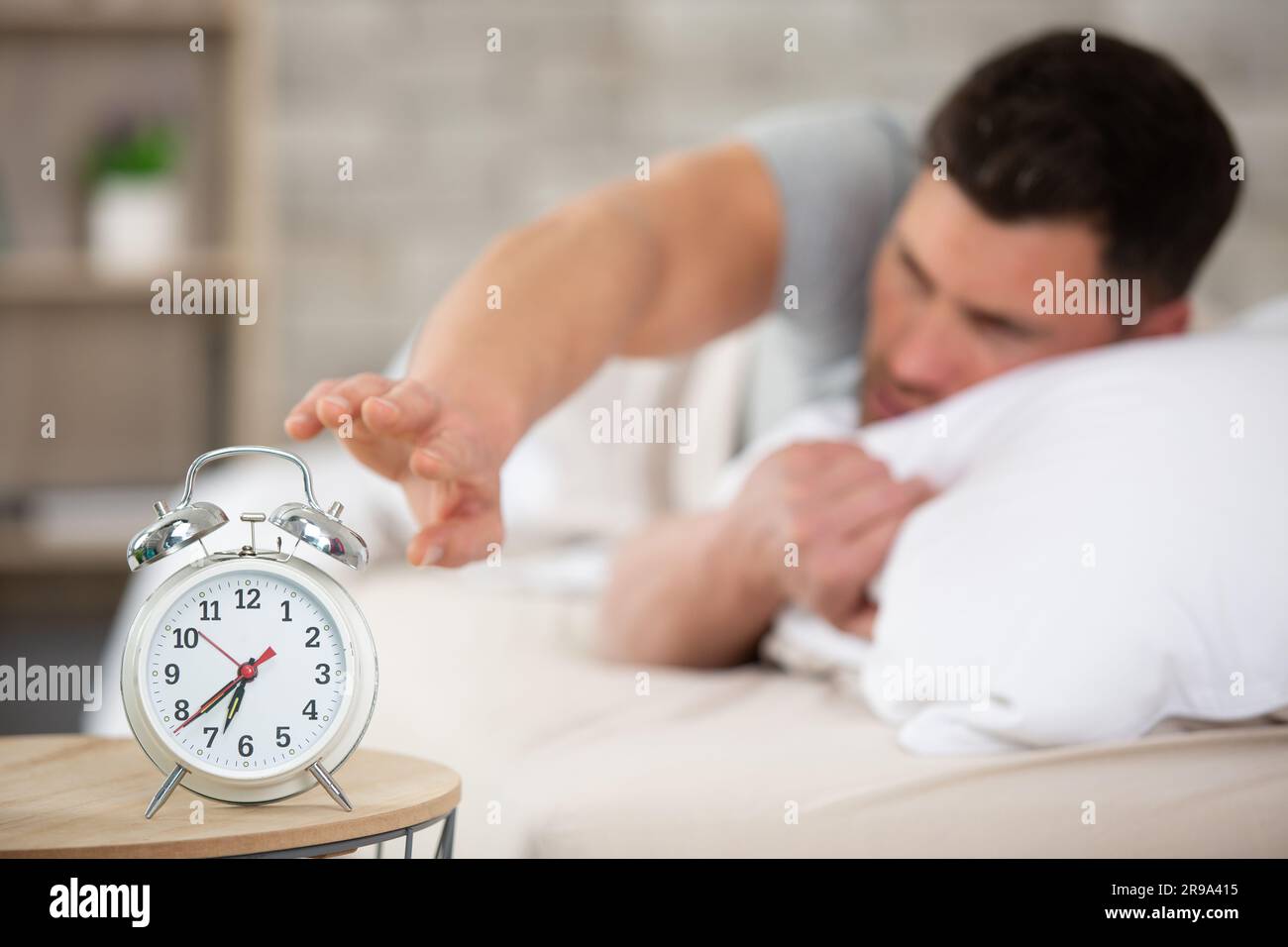 man waking up with alarm clock in bedroom Stock Photo - Alamy