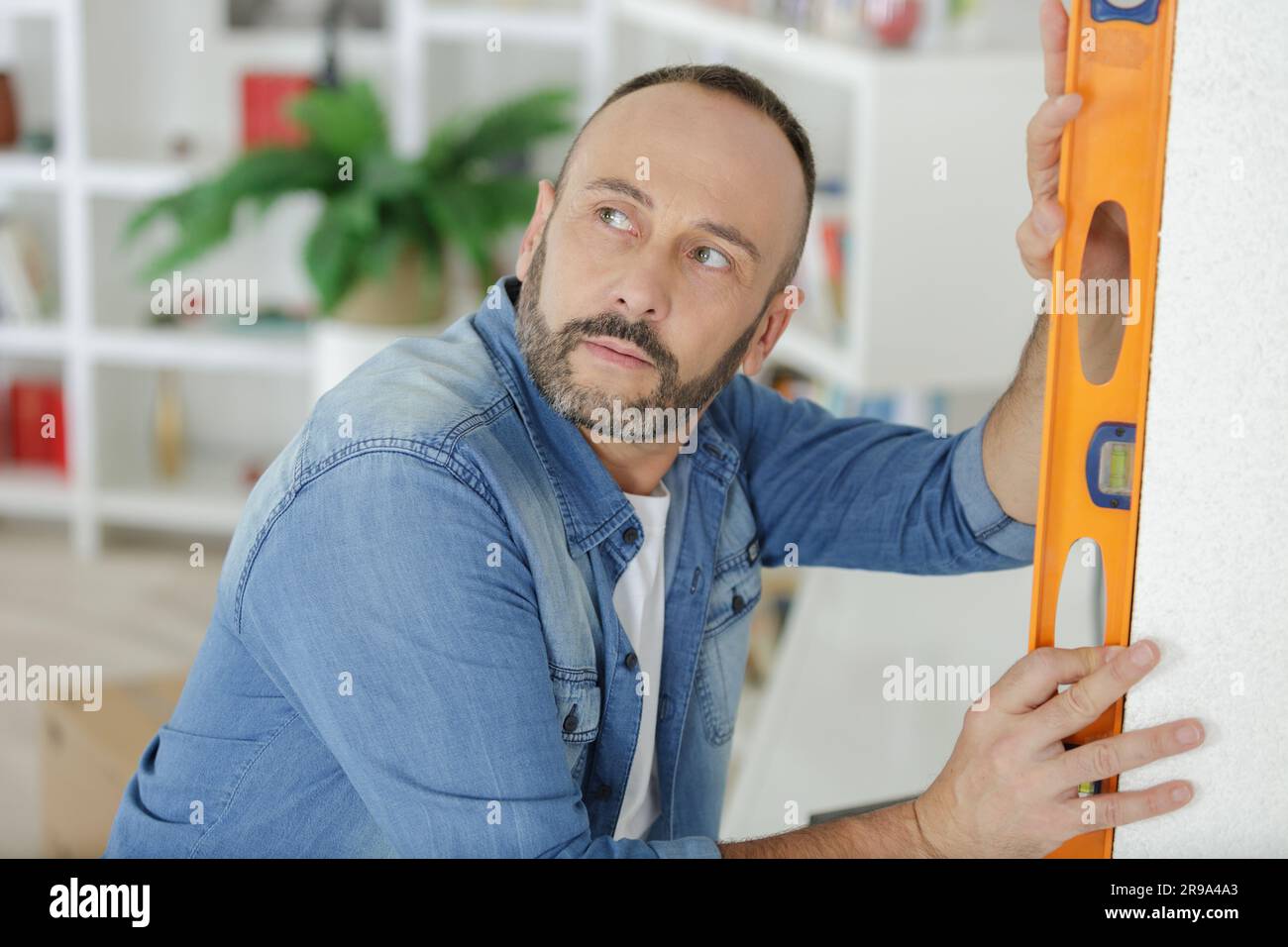 a middle aged man measuring wall Stock Photo - Alamy