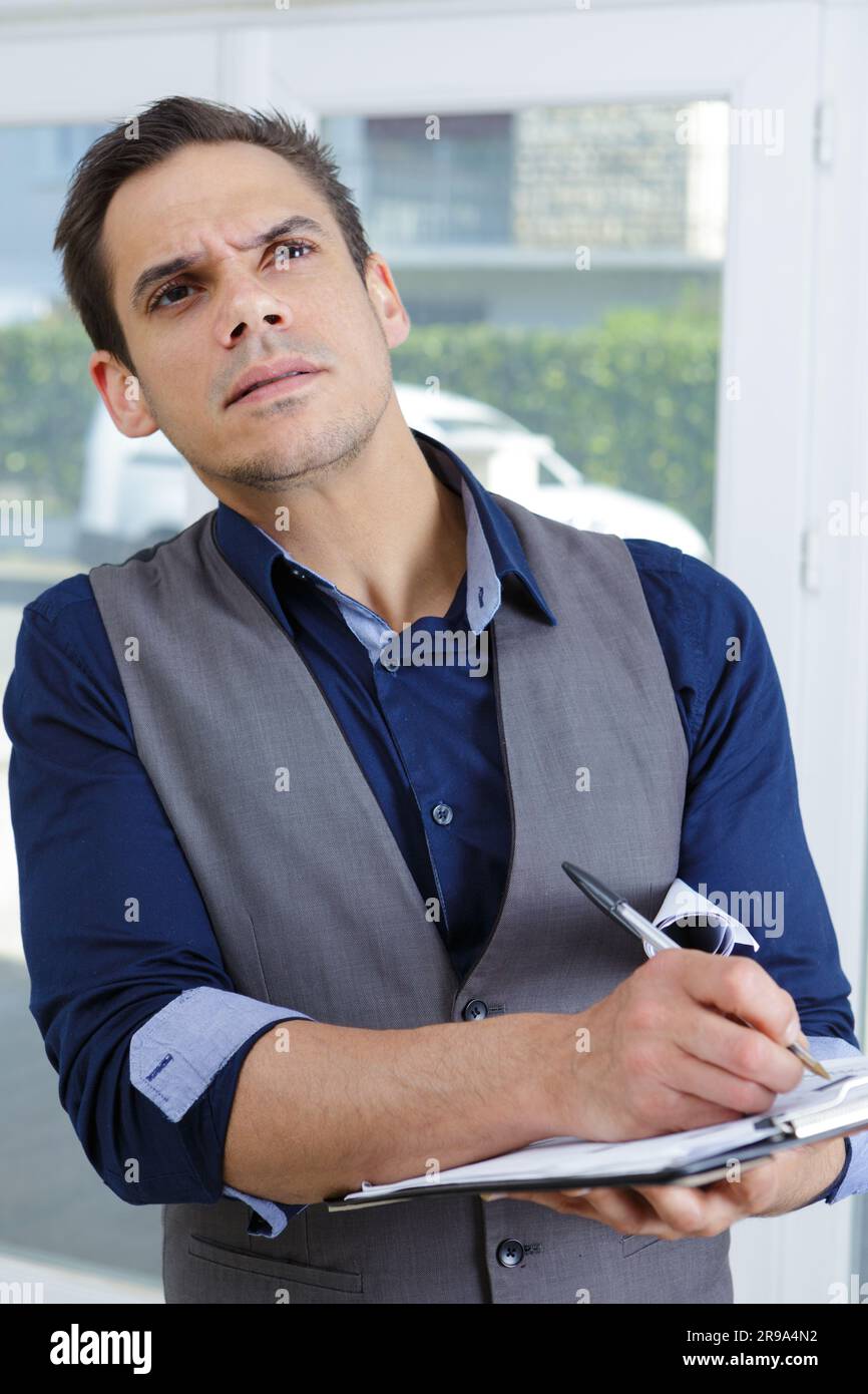 smartly dressed man making notes on clipboard Stock Photo - Alamy