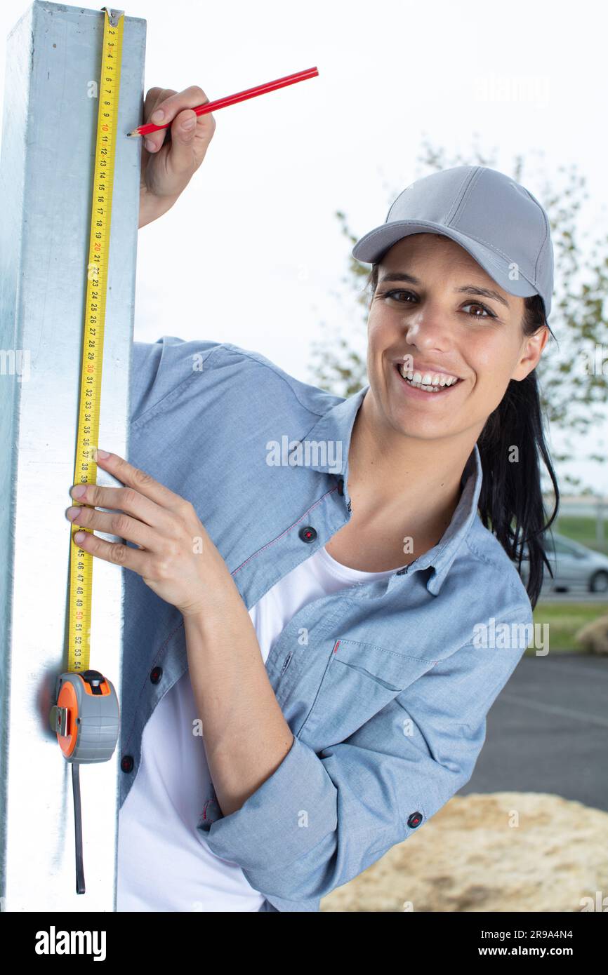 female construction worker carefully taking measurement with measuring ...