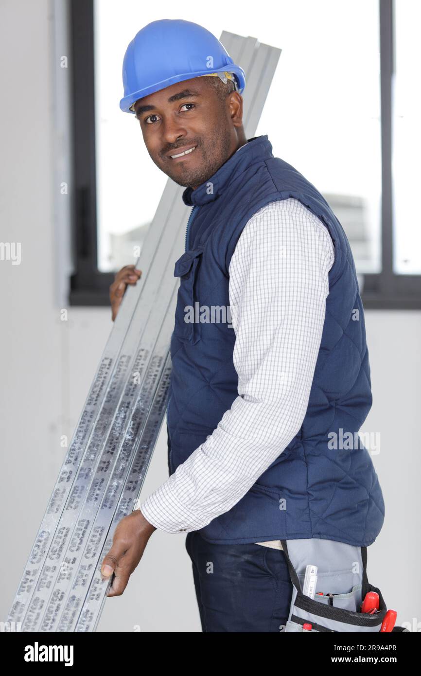 blue-collar worke carrying a heavy metallic bars Stock Photo - Alamy