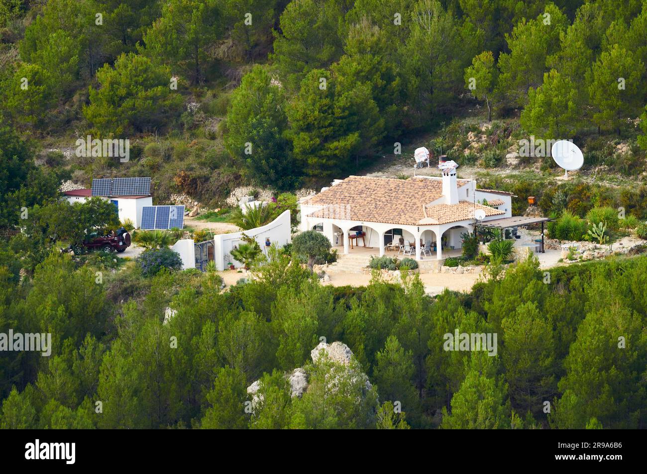A typical Mediterranean cottage with solar panels between pines in ...