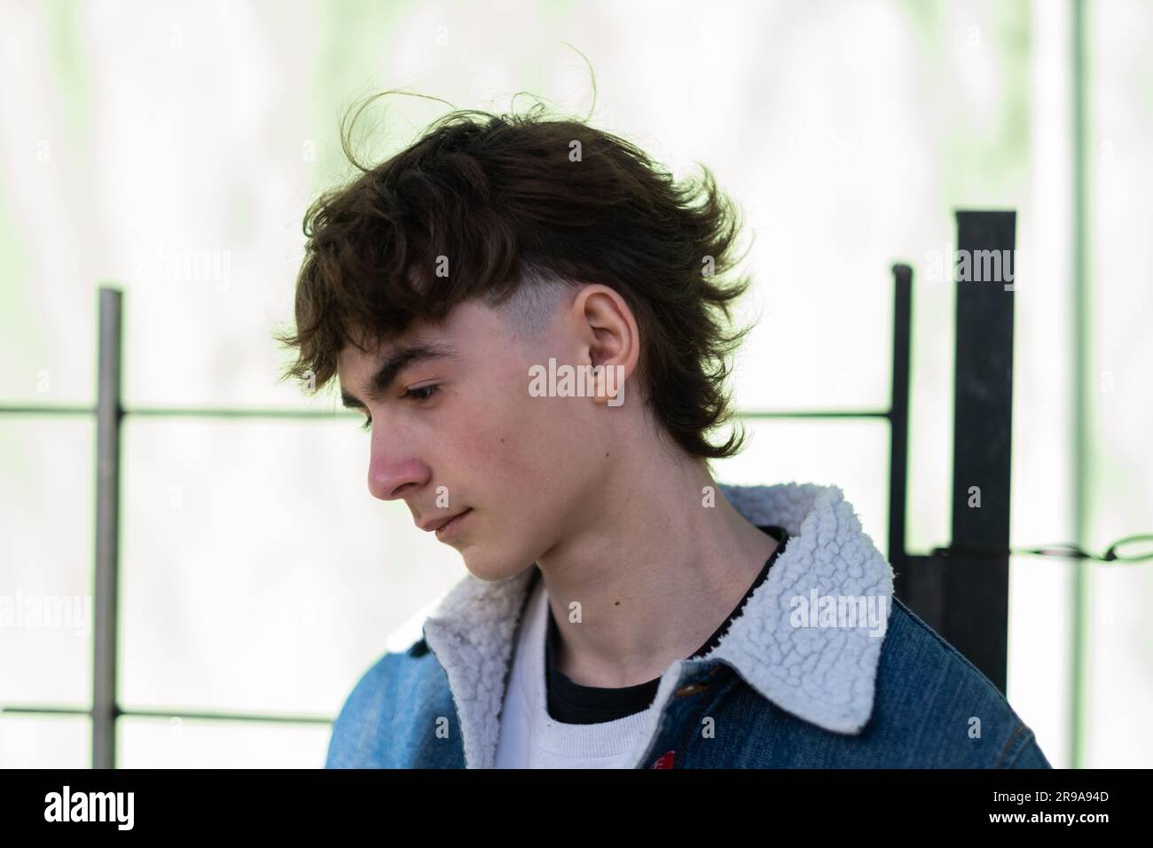 Side profile of a handsome young man wearing a denim jacket and leaning ...