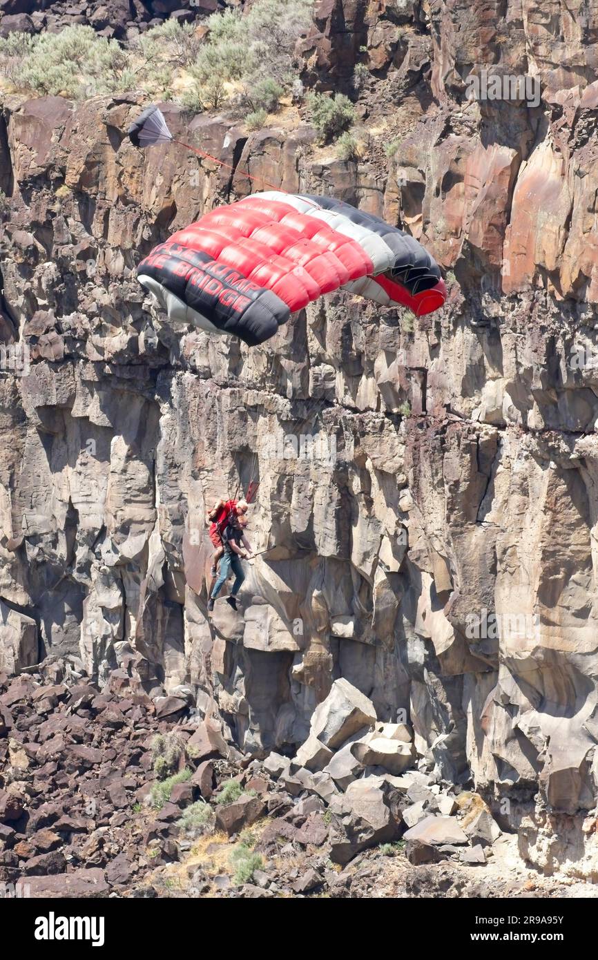 Tandem base jumpers soaring down the canyon after jumping off the bridge at Twin Falls, Idaho ...