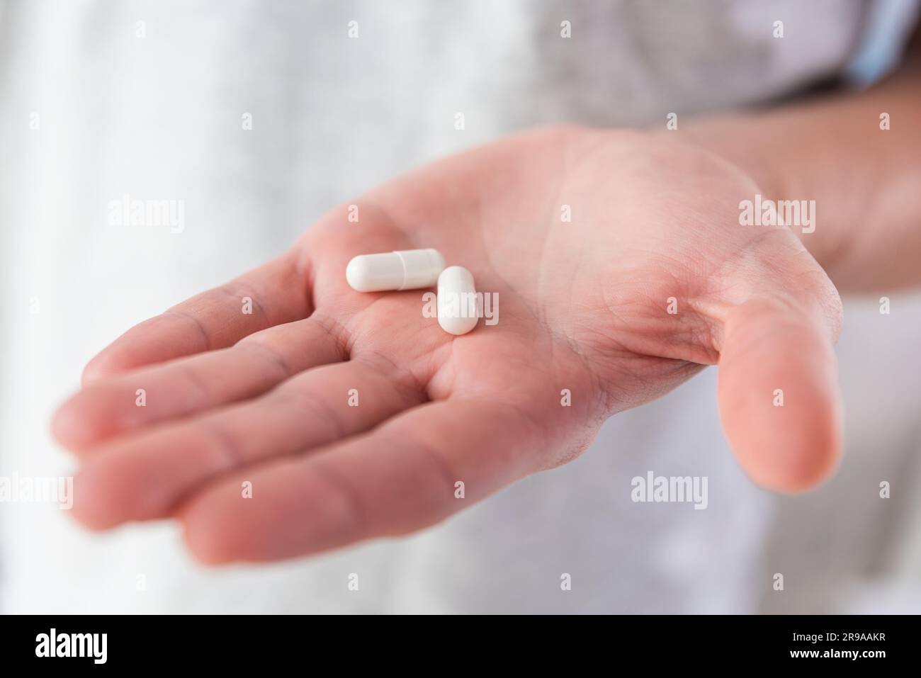 White capsules with collagen in male hand. Nutritional supplement ...