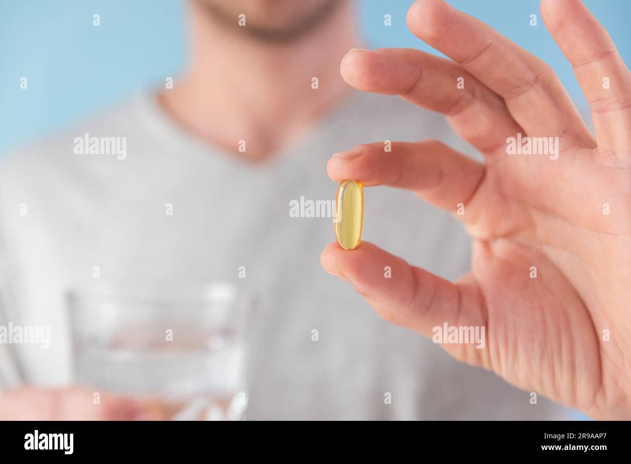 Dietary supplements. Man holding omega 3 capsule with glass of water. Morning dose of vitamin D ...