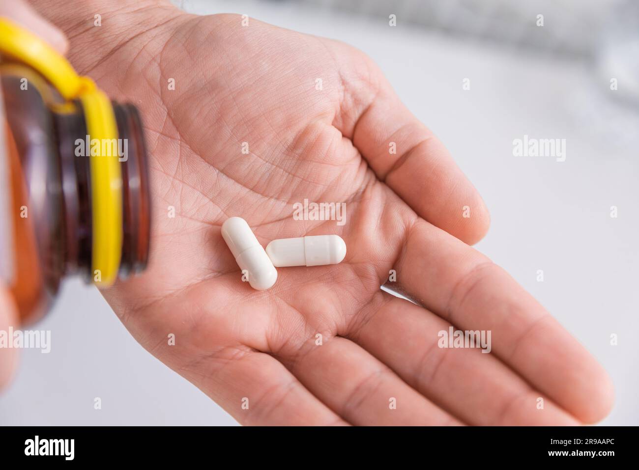 Man pouring white capsules with collagen in male hand from medicine bottle. Nutritional ...