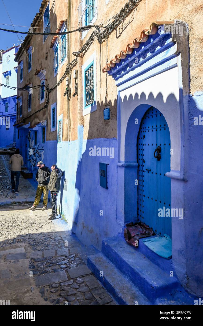 A dramatic, big Blue door in the shade of sunset with typical small ...