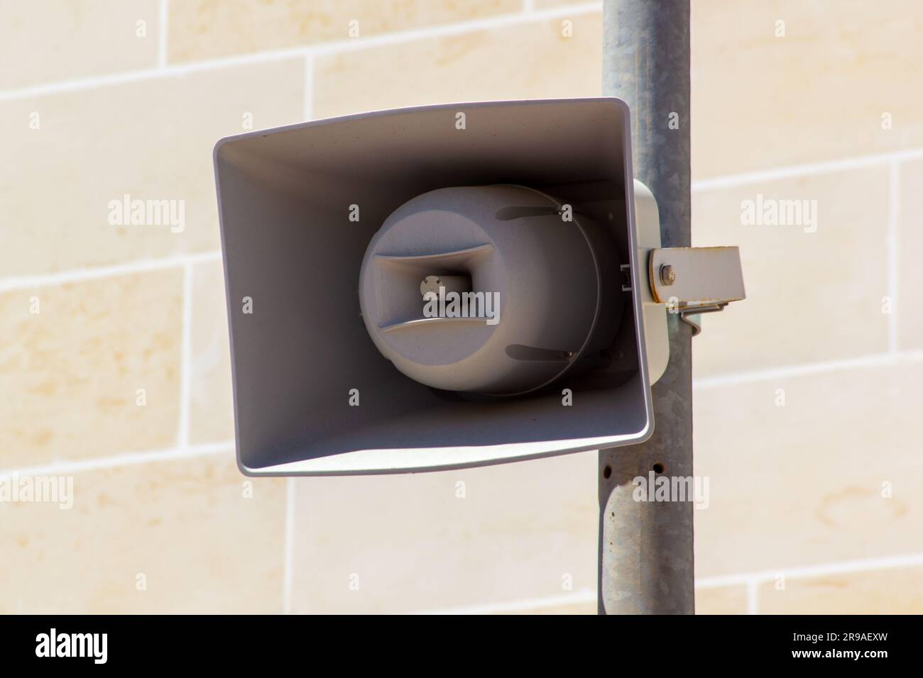 A low angle shot of a speaker on a pole against a building under the ...