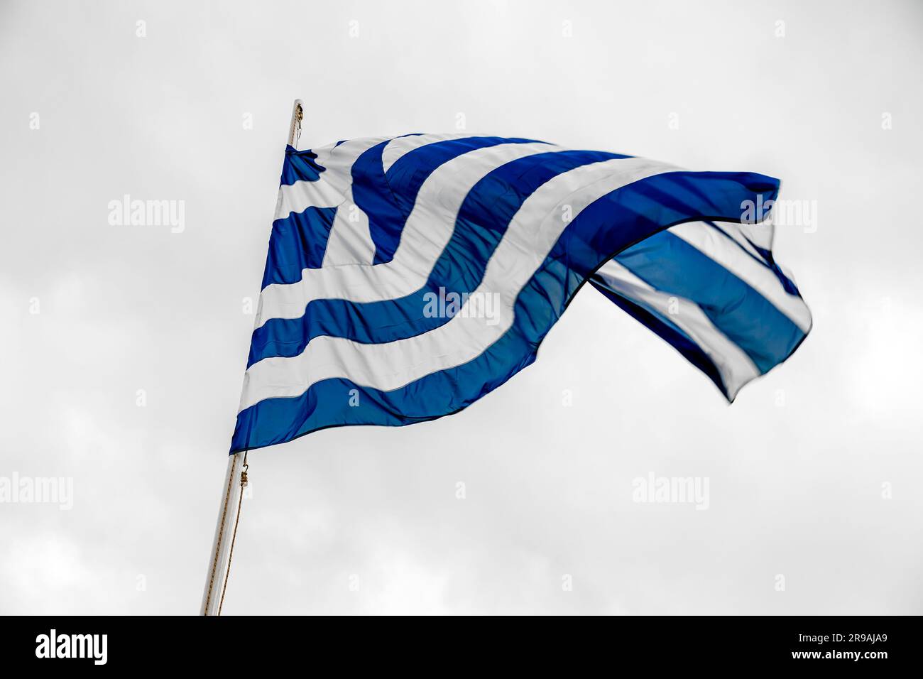 Fabric Greek flag waving on a flag pole against the sky Stock Photo - Alamy