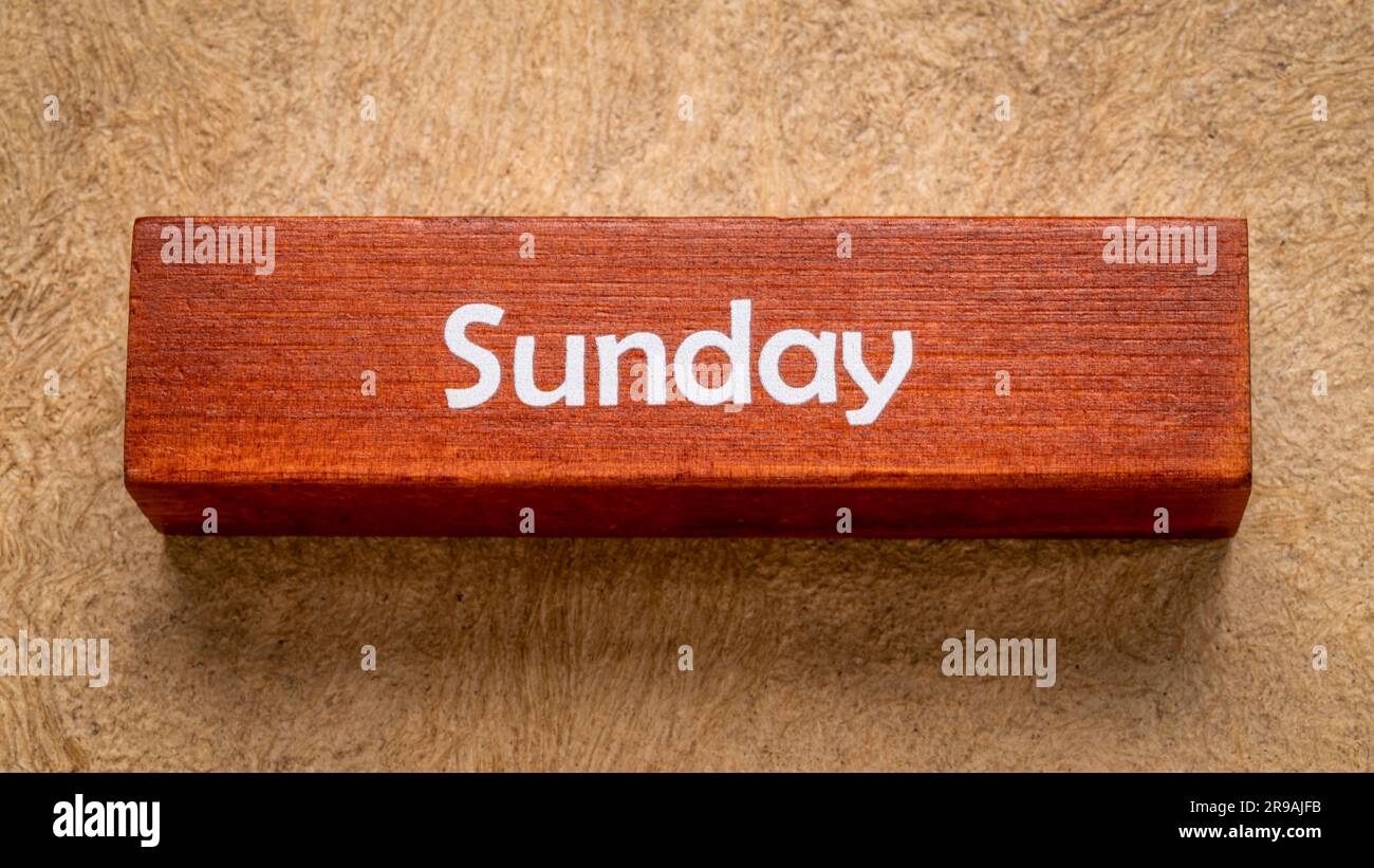 Sunday text on wooden block against handmade bark paper in earth tones ...