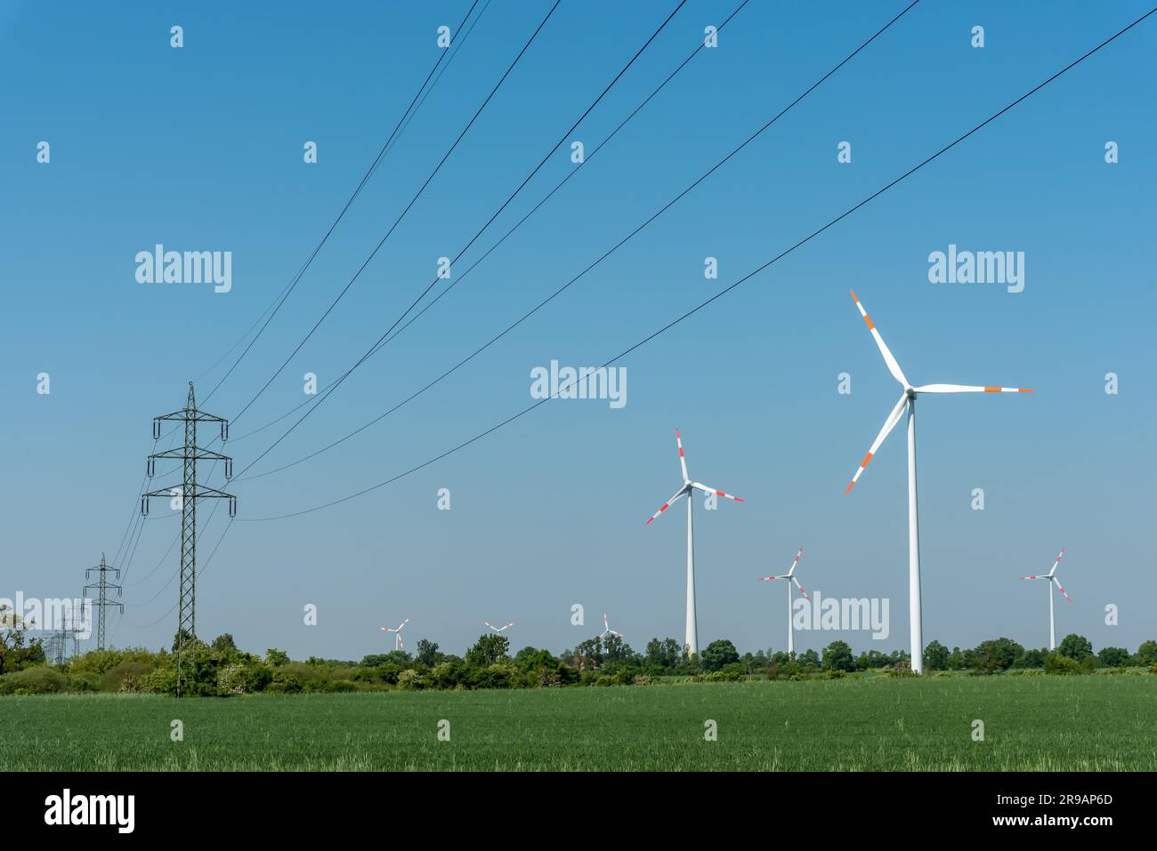 Overhead power lines and wind turbines against a blue sky seen in ...