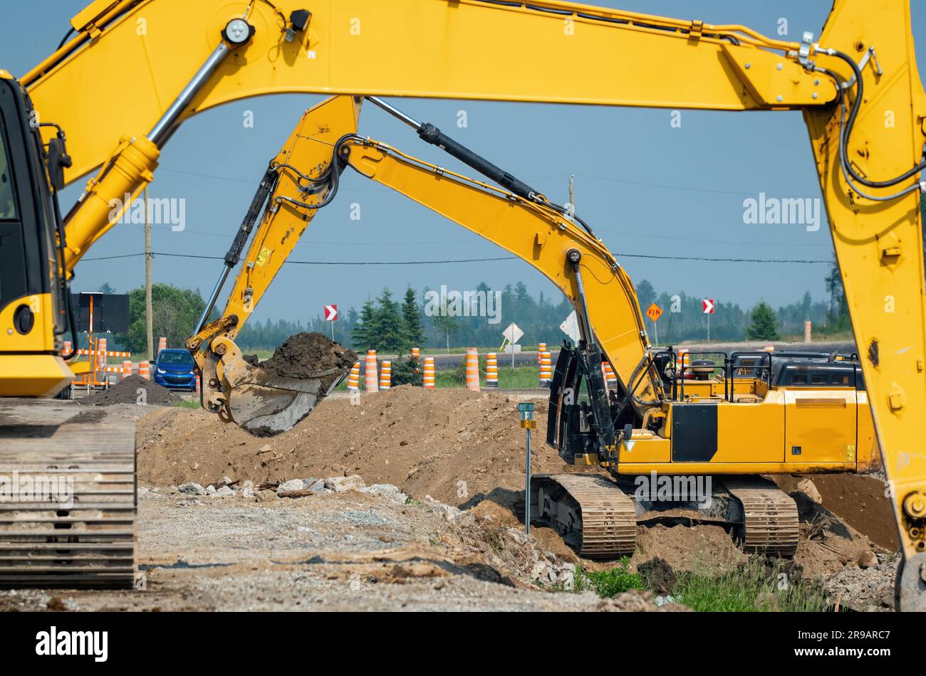 Two yellow excavators working on a road construction site with road ...