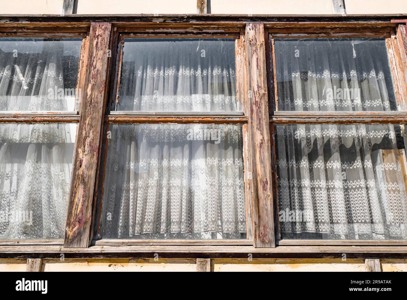 Worn old windows with vintage curtains on an old building in a cottage ...