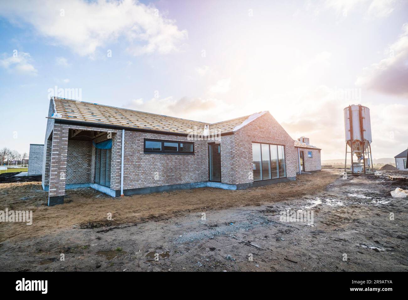 New brick house at a construction site with a large silo in the morning ...