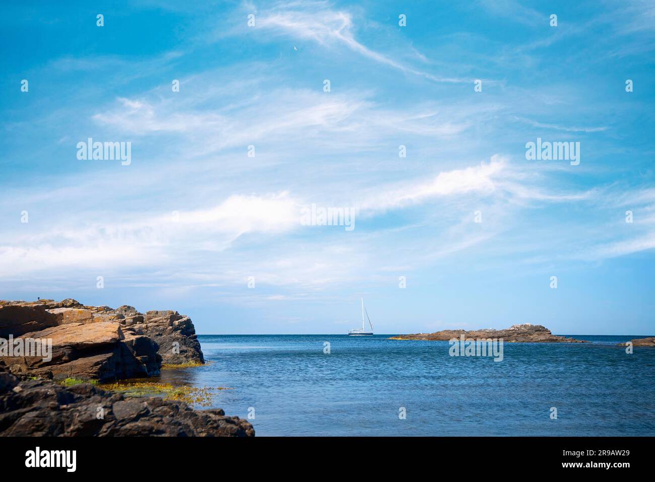 Sailboat on the sea under a blue sky with cliffs by the shore in the ...