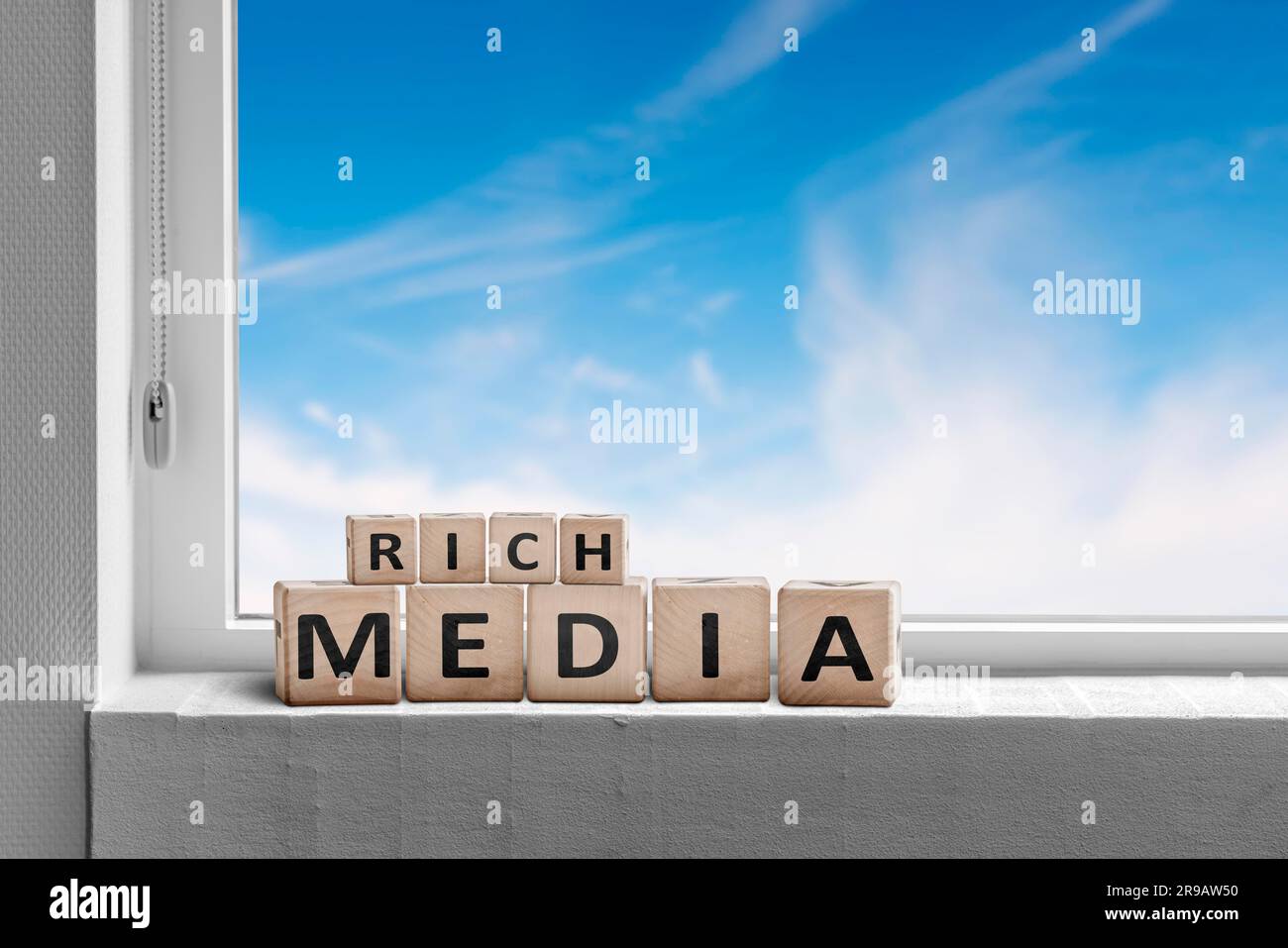 Rich media sign written on wooden blocks in a window with a blue sky ...