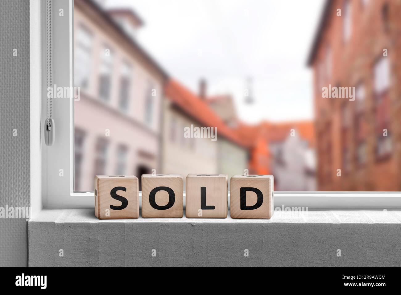 Sold word made with cubes in a window in a city with a view to ...