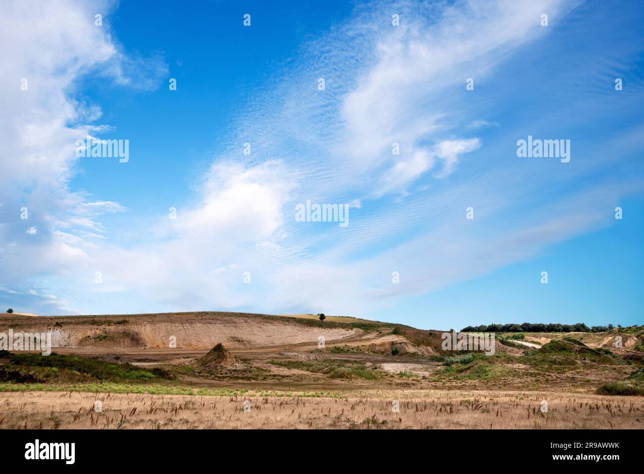 Gravel pit in a rural landscape with dry flora under a blue sky in the ...