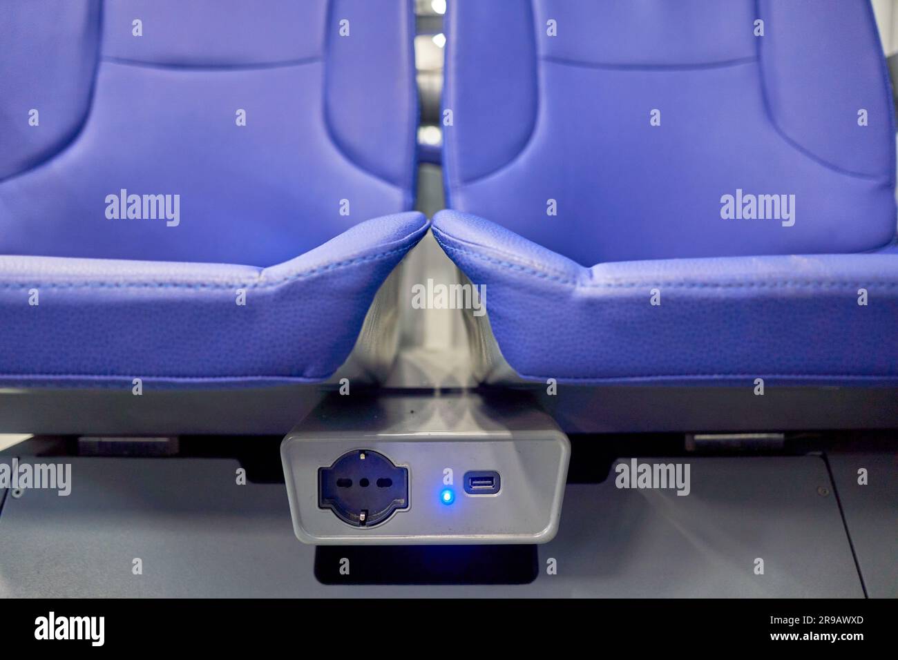 A low-angle view of blue train seats complete with charging ports for ...
