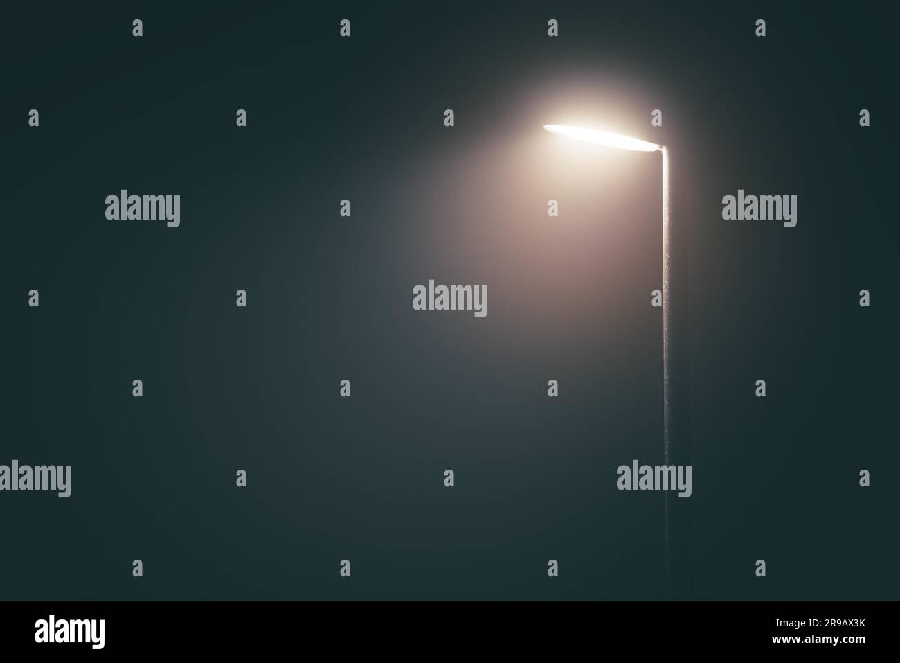 Streetlight post with bright light in a misty fog in the evening in a ...