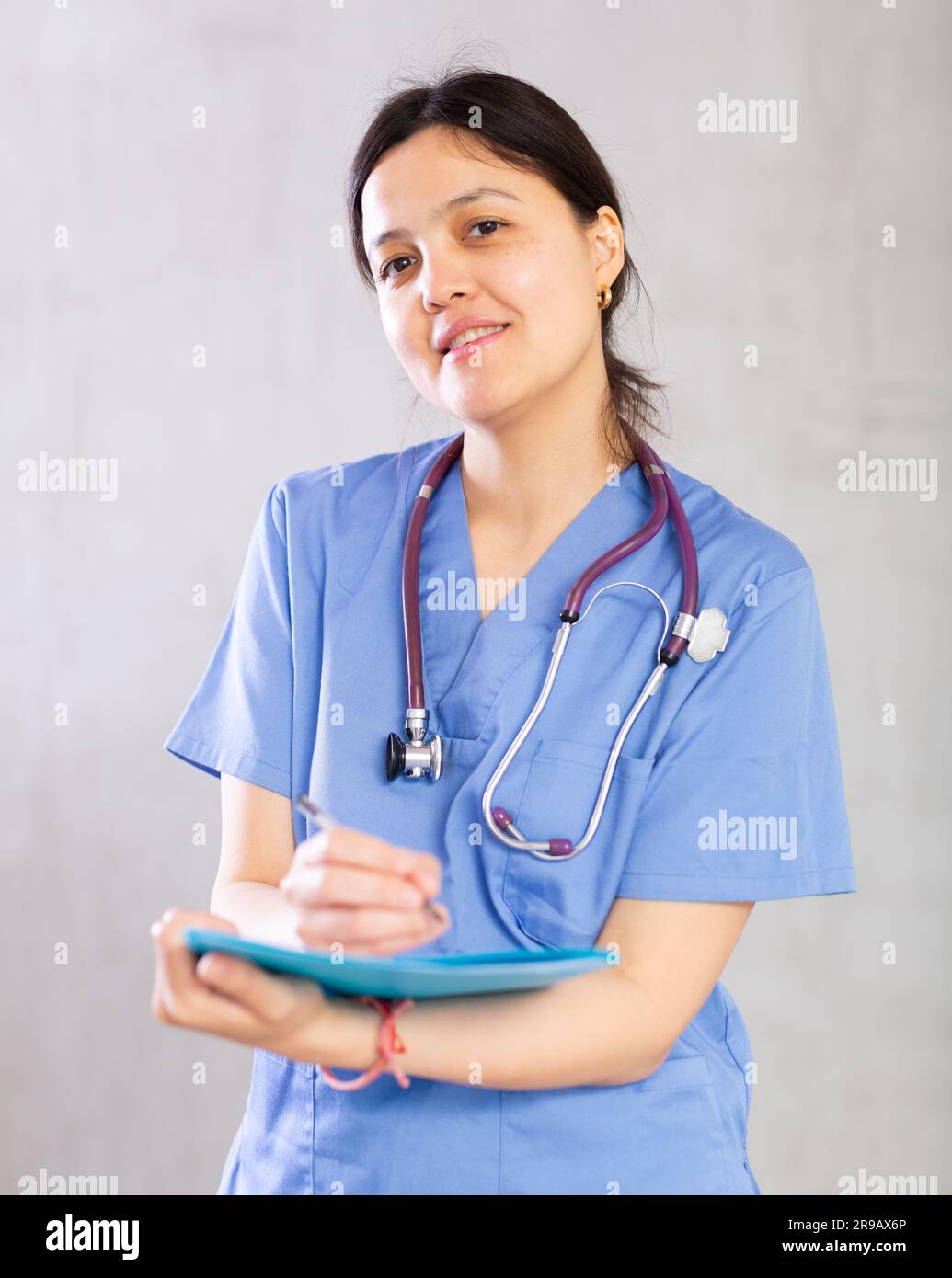 Polite woman doctor in blue uniform filling out medical records Stock ...