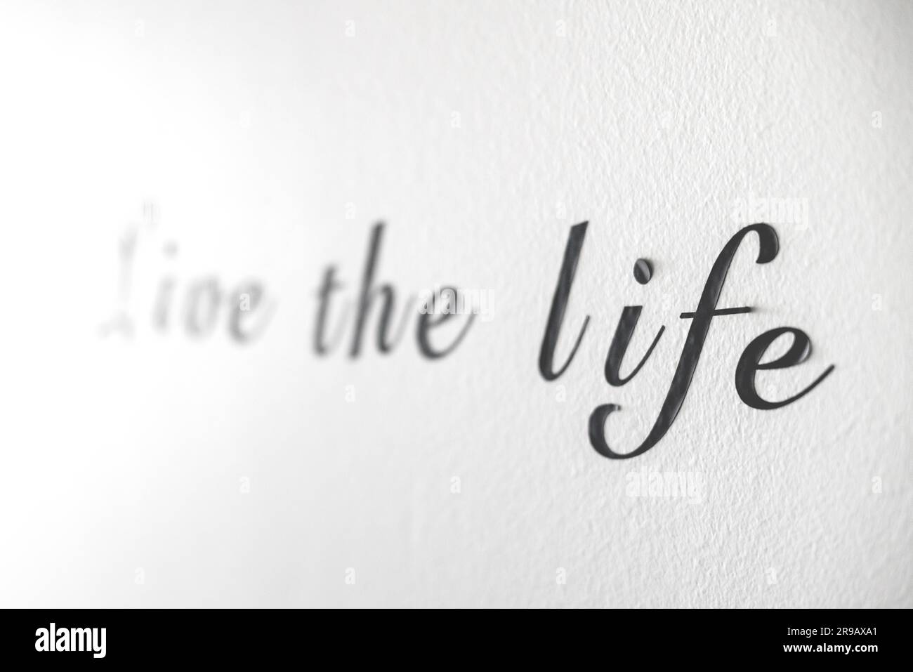 Live the life word phrase on a white wall written with black letters ...
