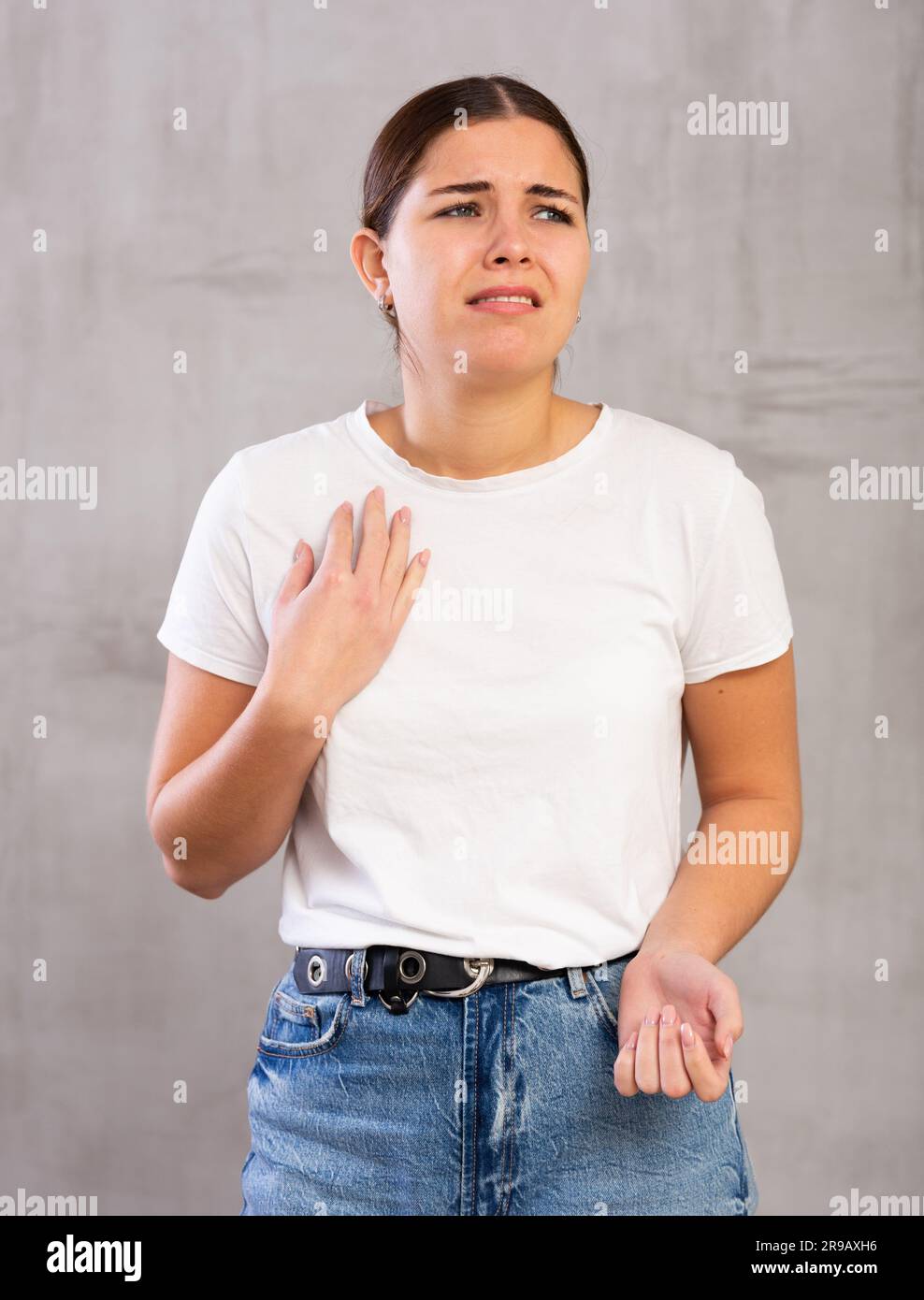 Sad young woman posing crossly against gray background Stock Photo - Alamy