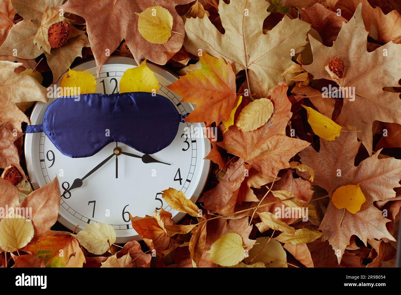 autumn background with clock, sleeping mask and leaves Stock Photo - Alamy