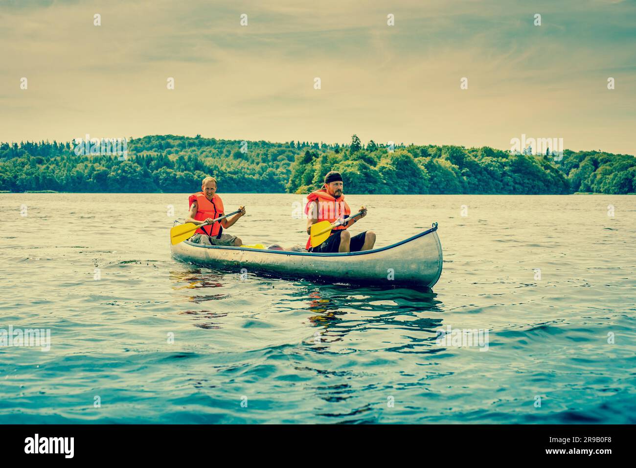 Men sailing a canoe in a beautiful lake scenery Stock Photo - Alamy
