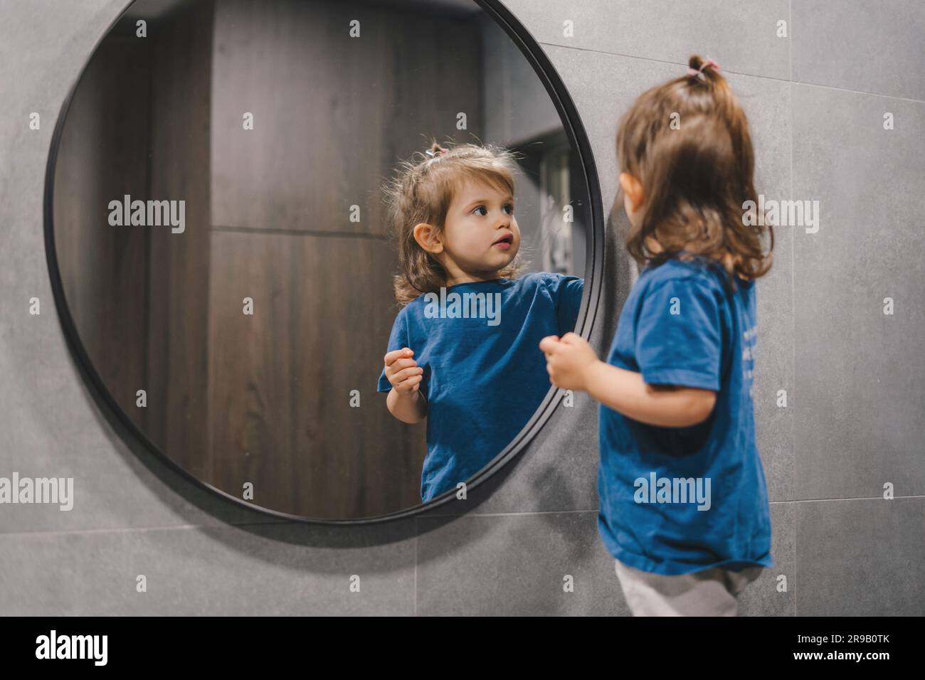 Curious Little Girl Admiring Herself in the Mirror Stock Photo - Alamy