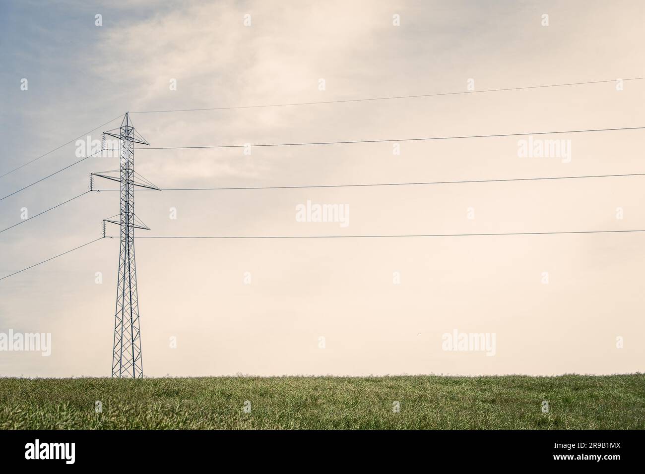Tall pylons with wires on a green field Stock Photo - Alamy