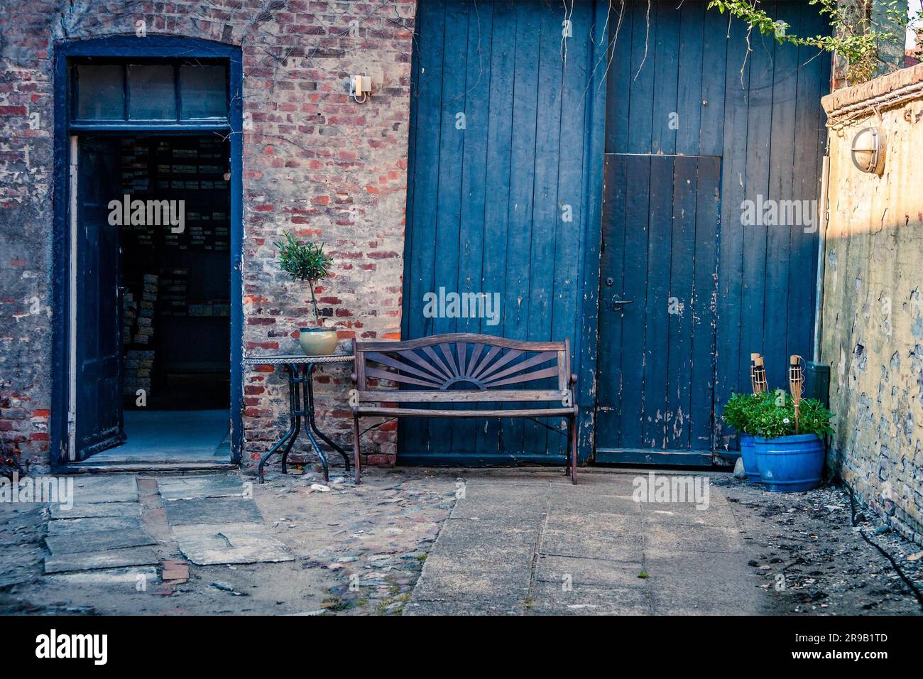 Bench at a house facade with a blue gate Stock Photo - Alamy