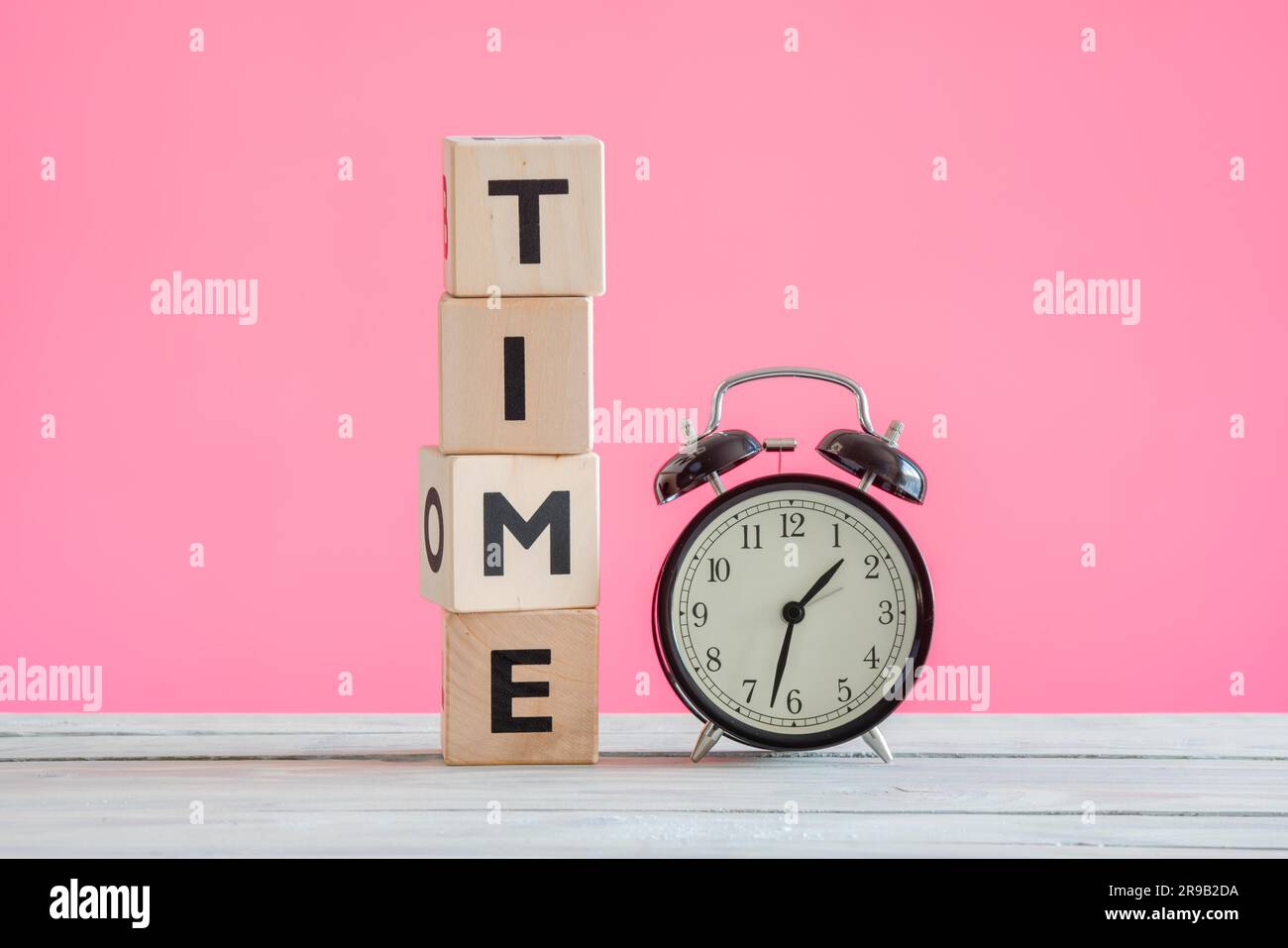 Alarm clock and cubes spelling time on a pink background Stock Photo ...