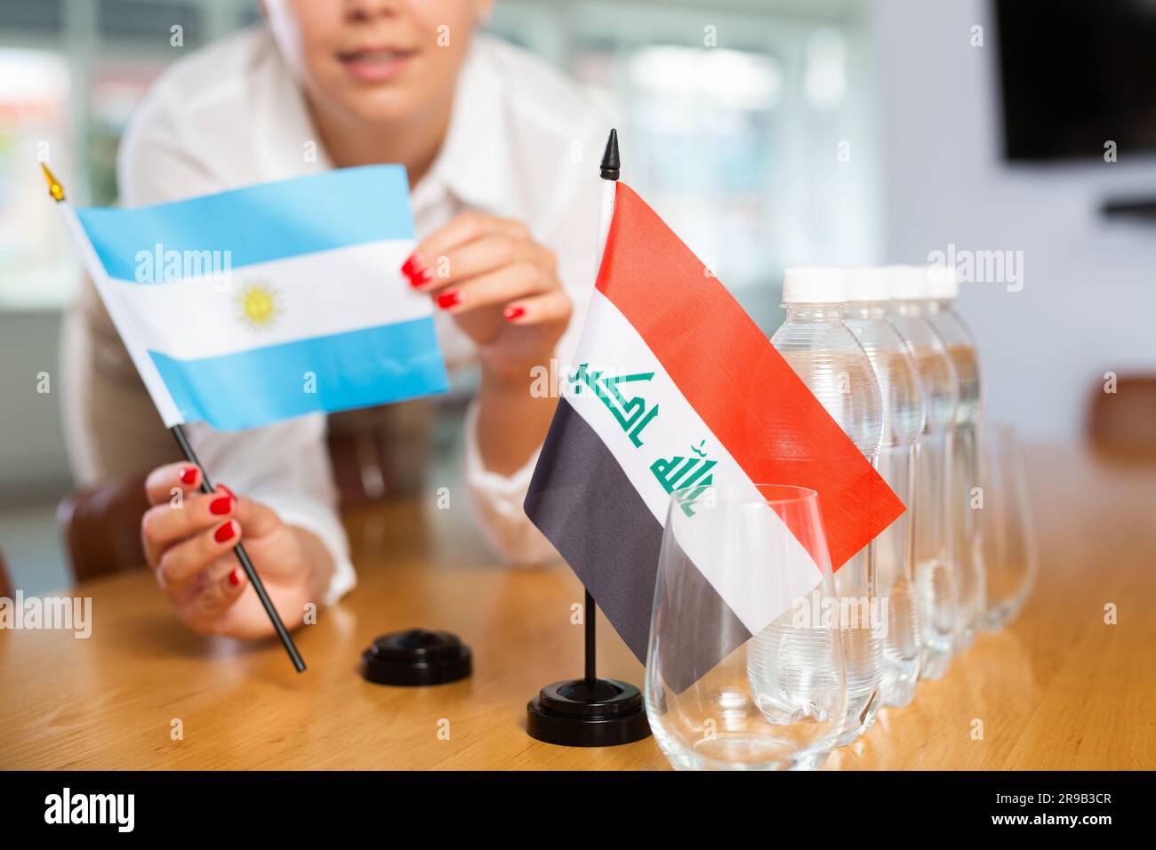 Woman secretary prepares an office for negotiations - she places flags ...