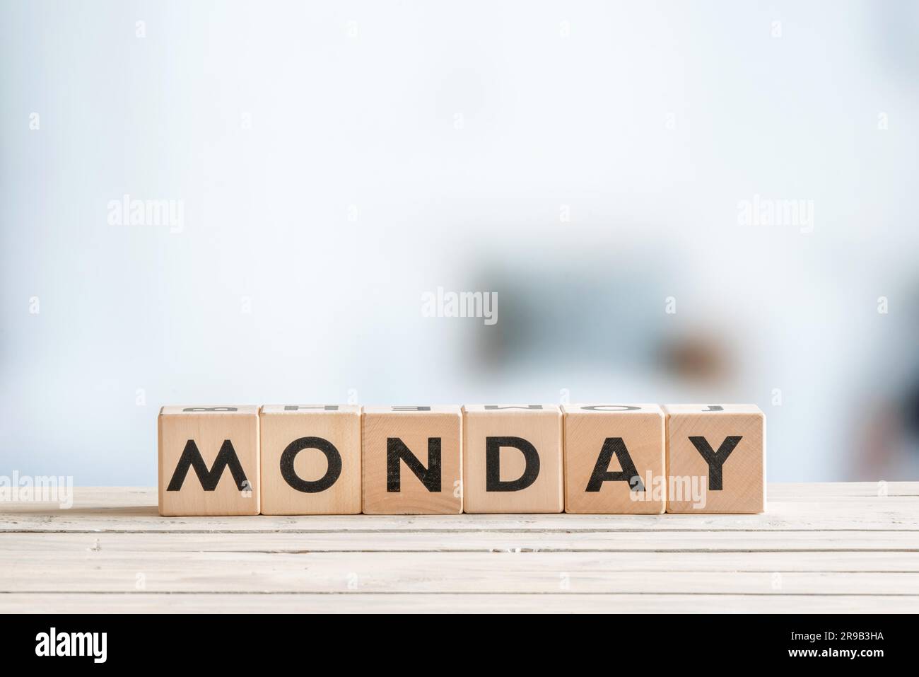Monday sign on an indoor table with blue background Stock Photo - Alamy