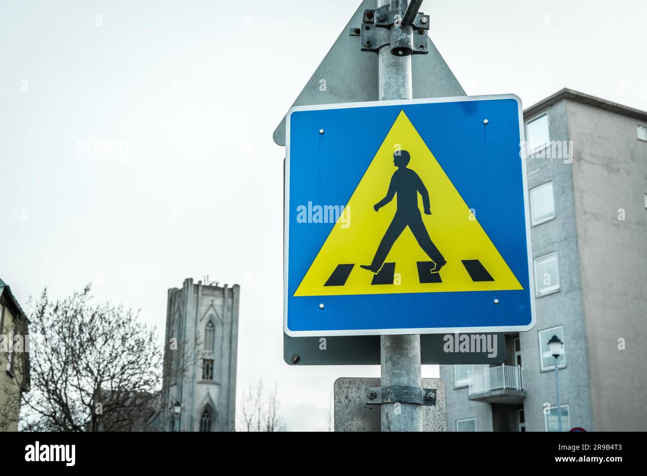 Pedestrian crossing sign in blue and yellow in a big city Stock Photo ...