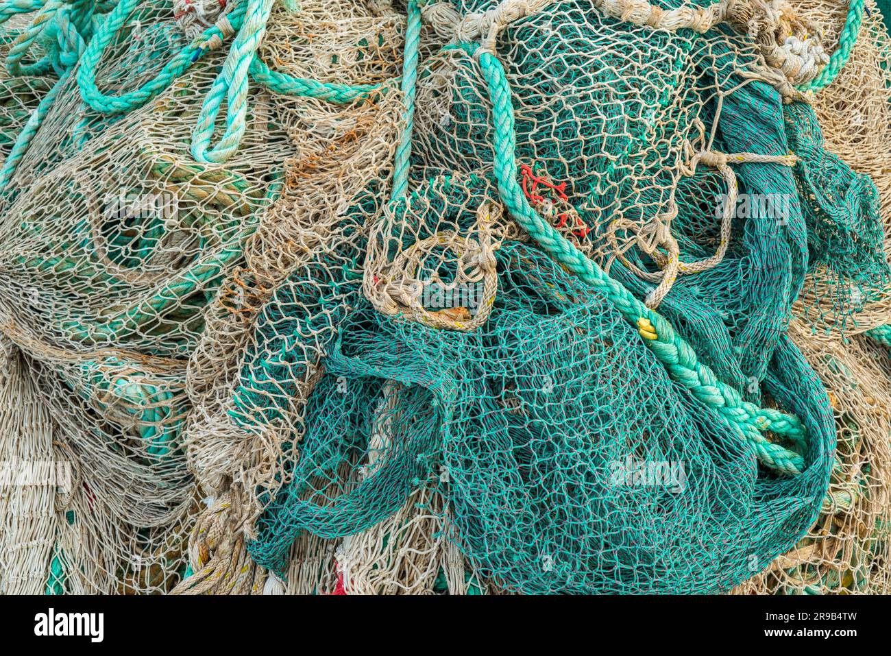 Fishing net in various colors by a harbor Stock Photo - Alamy