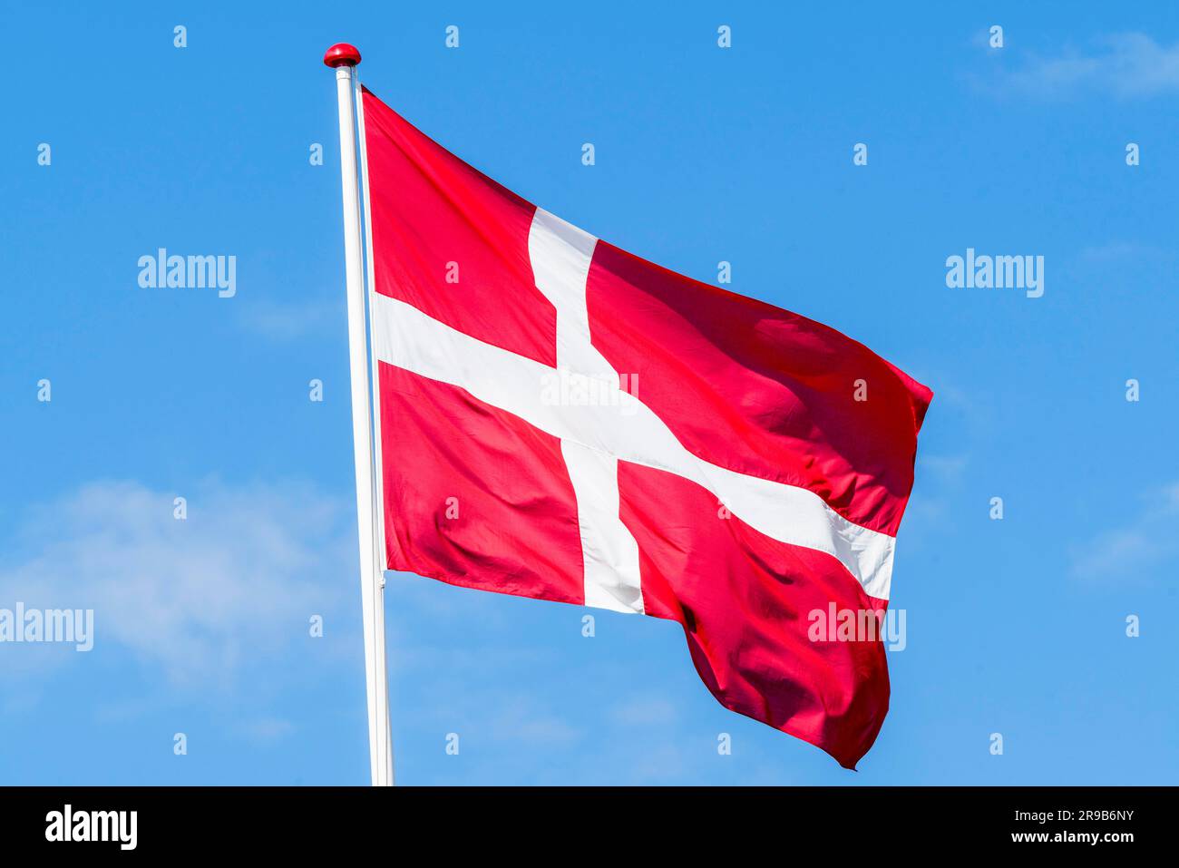 Flag of Denmark in red and white colors waving in the wind on a blue ...
