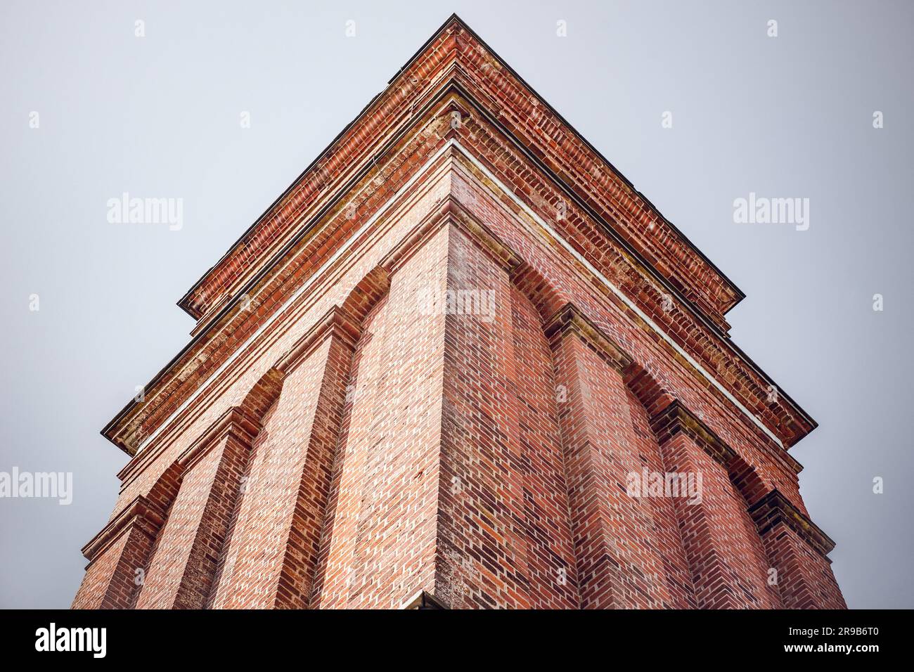 High tower with red bricks from below on a grey and blue background ...