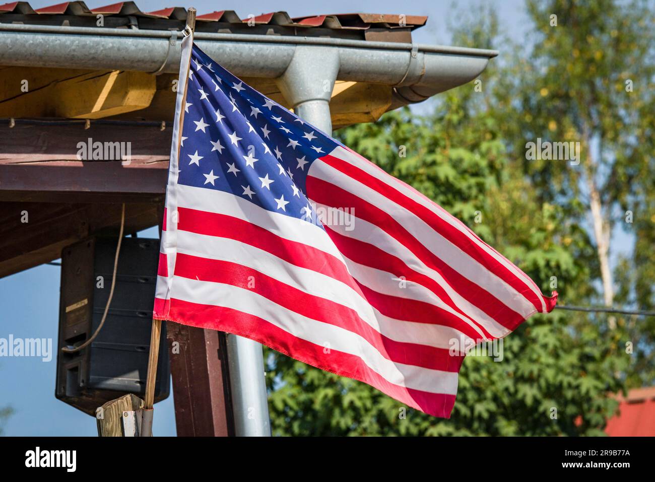 American flag on a porch outside a small cabin in the wild west in the ...