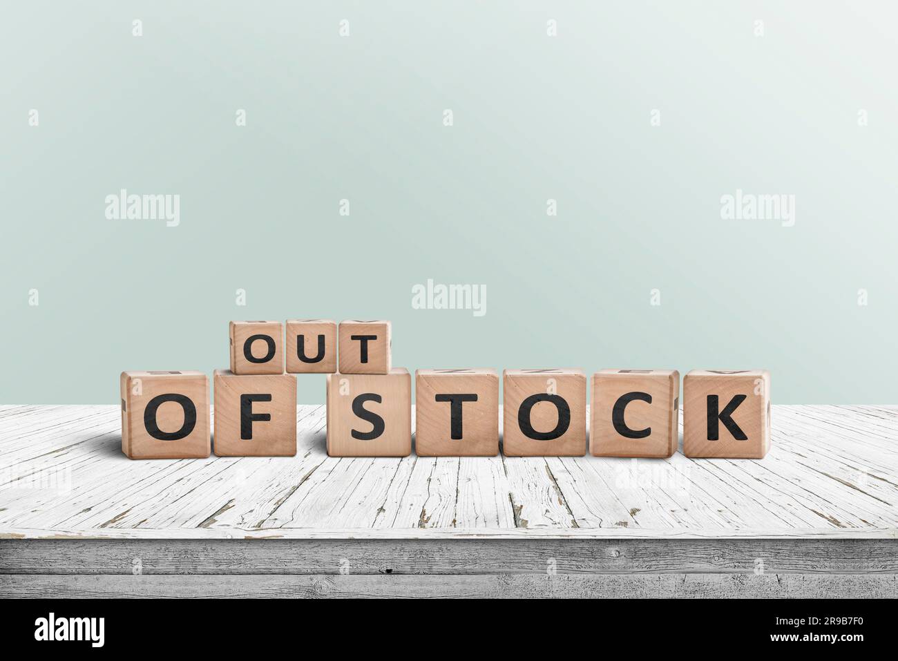 Out of stock sign standing on a wooden table with a green wall in the ...