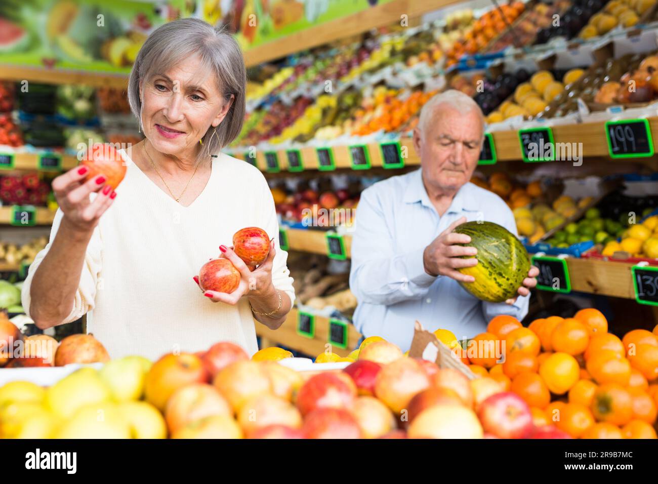 Mature woman and man selecting fruits in greengrocer Stock Photo - Alamy