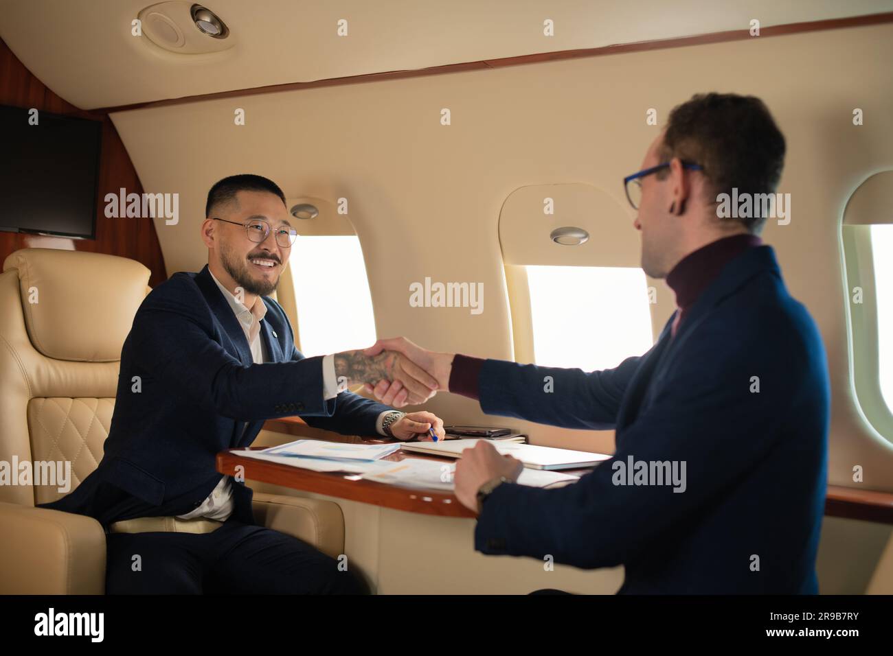 Two CEO young businessman couple sitting inside a private jet airplane ...